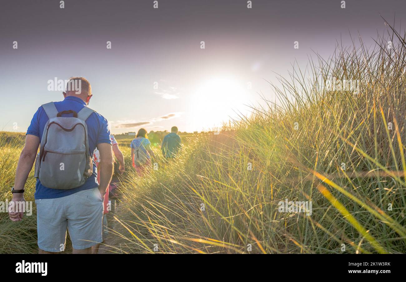 Small group a walkers walking along a path foot in late evening sun ...