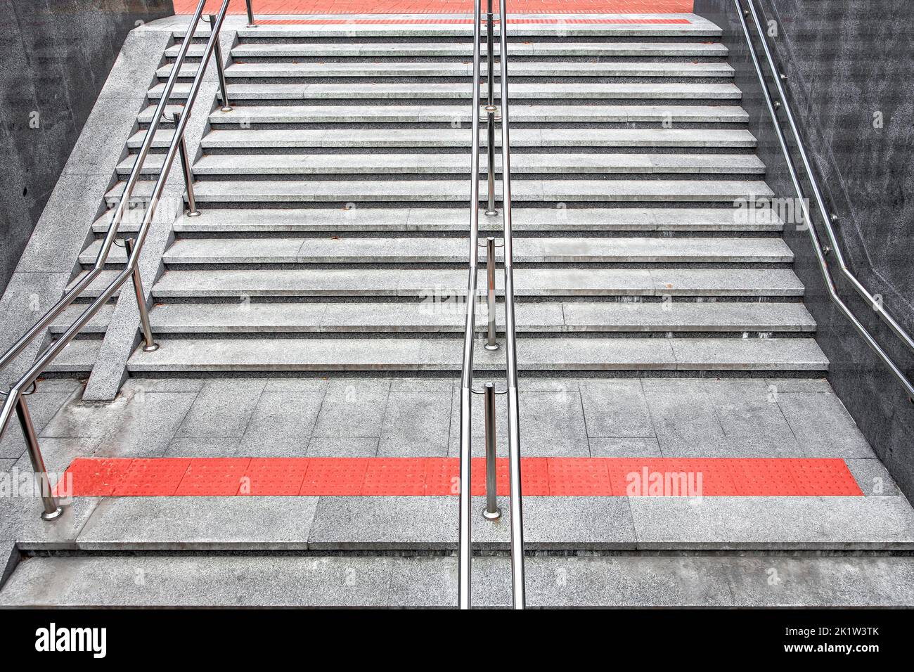 gray granite staircase with steps and stainless steel handrail descent ...