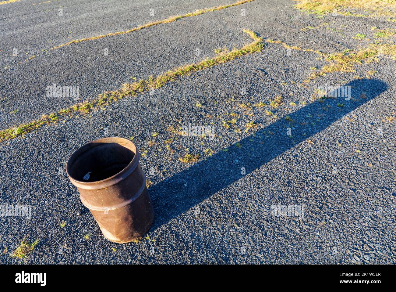 Garbage can in a metal barrel outside on asphalt at the parking lot ...