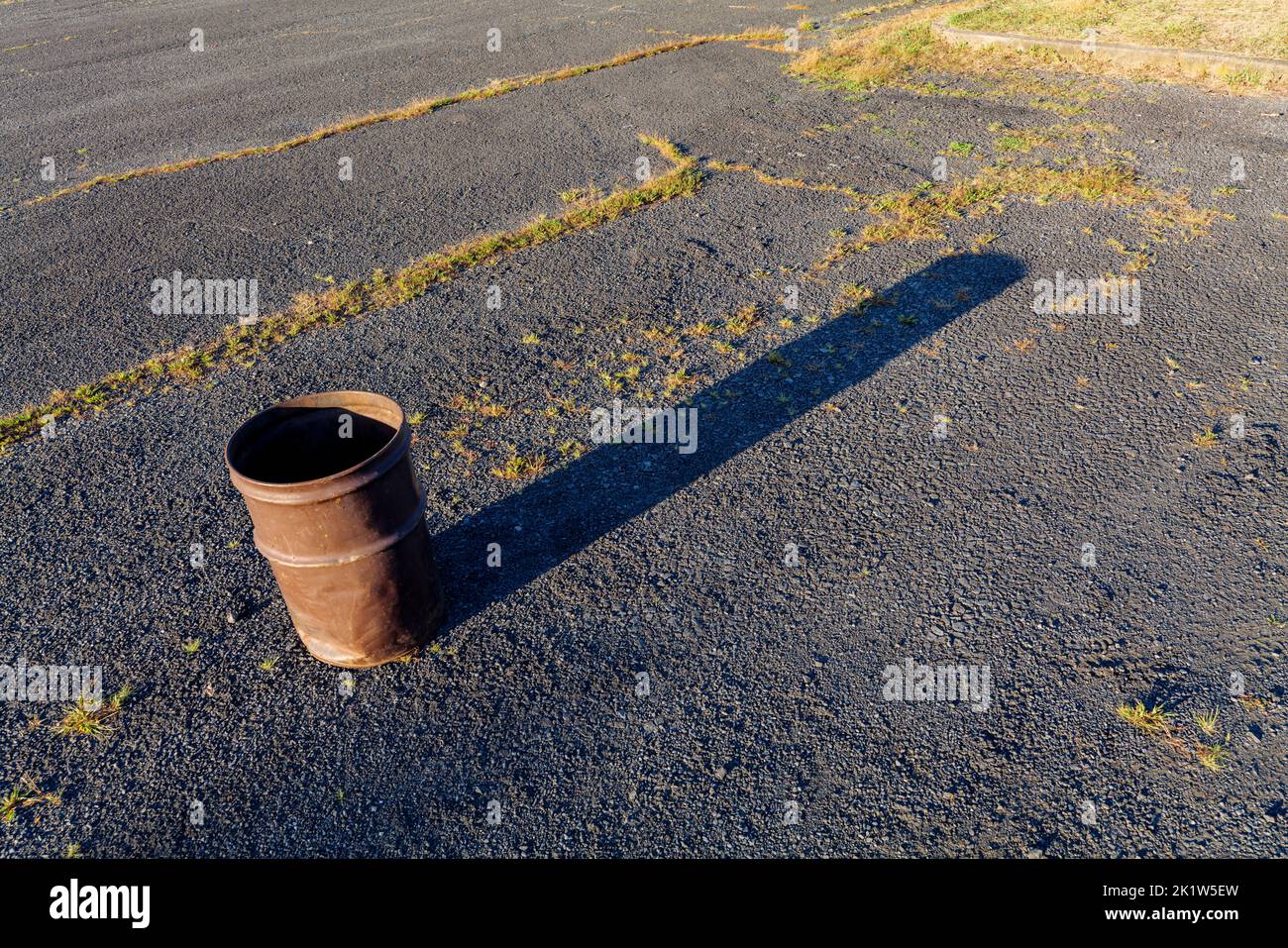 Garbage can in a metal barrel outside on asphalt at the parking lot ...