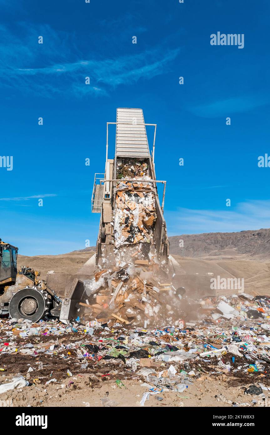 A trailer from a semitrailer truck is in a landfill tipper being raised ...
