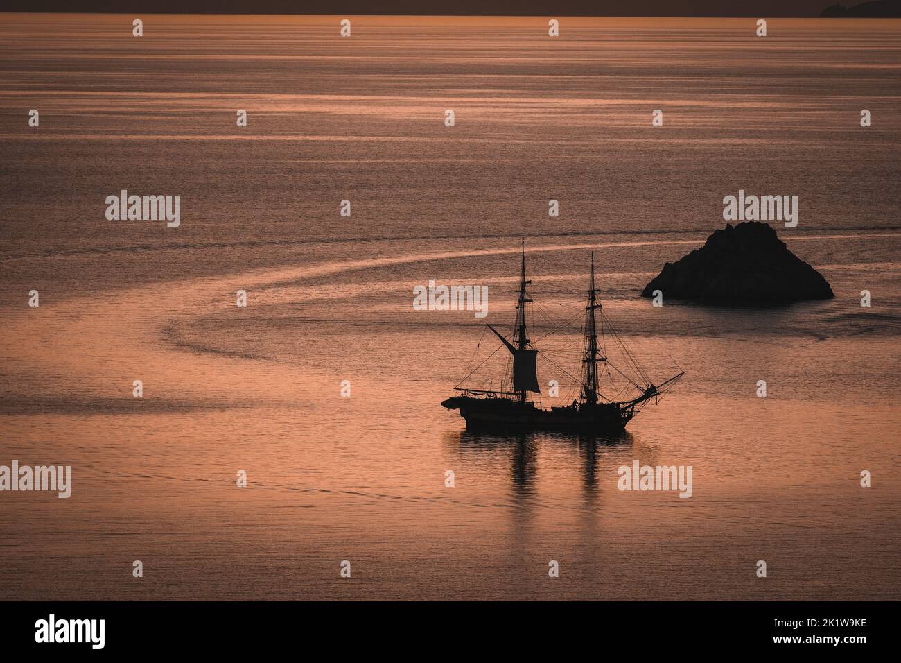 A silhouette of a ship sailing in the sea at sunset Stock Photo - Alamy