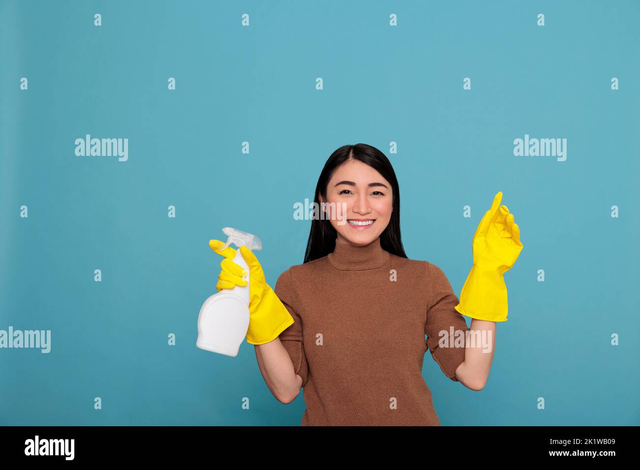 Asian happy glad housewife from daily work holding spray in yellow ...