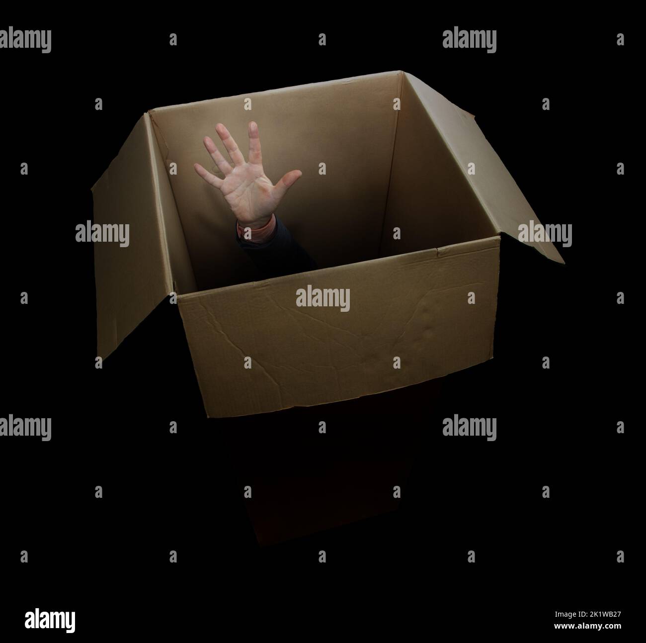 A man's hand raised up in a cardboard box, on black background Stock ...