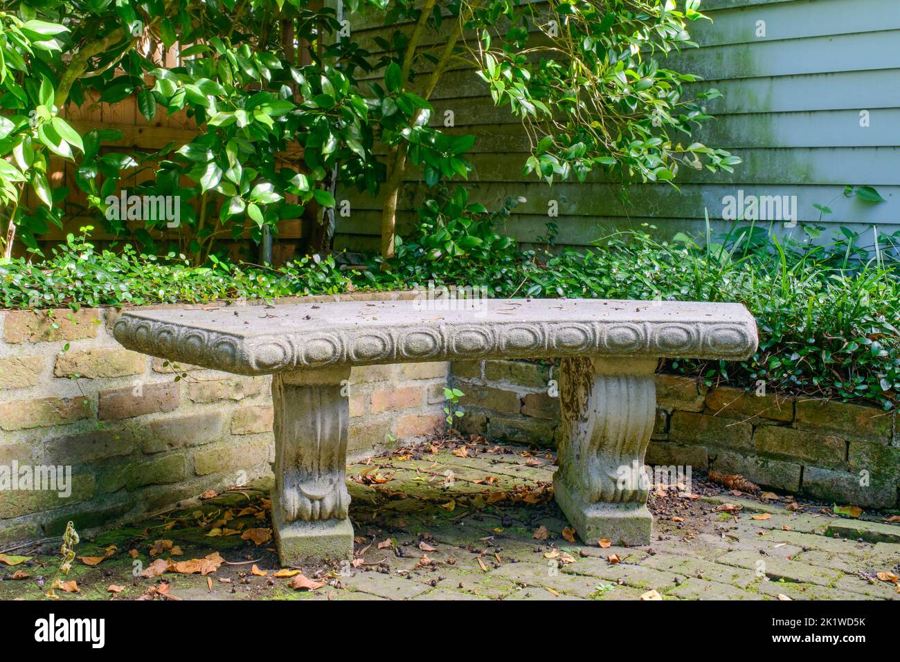 Closeup of concrete garden bench on brick patio of historic New Orleans ...