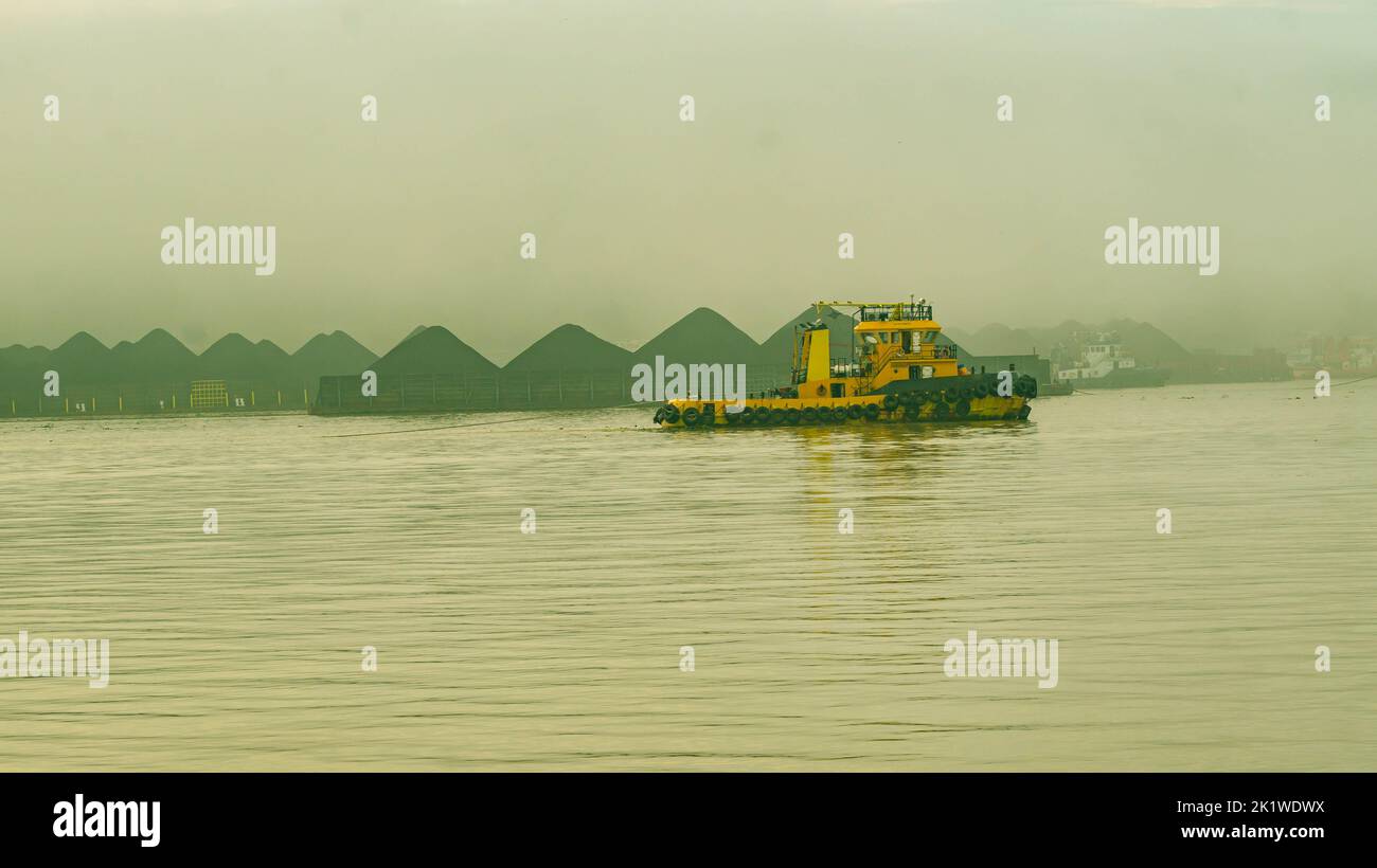 Morning traffic at Mahakam River, Samarinda. Tugboat towing huge barge ...