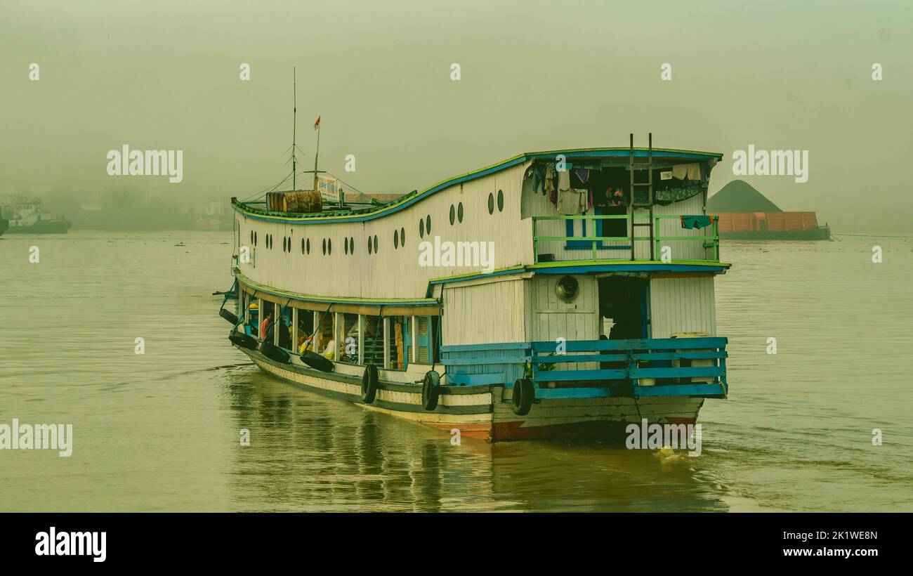 Long wooden boat loaded by passengers and goods cruising Mahakam River ...
