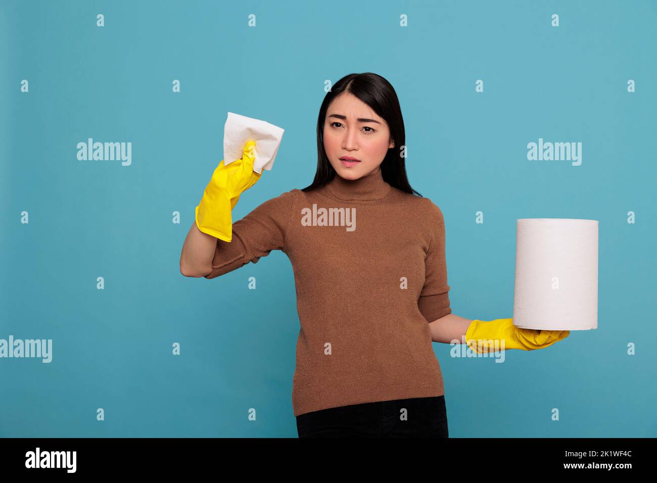 Angry sad and depressed asian houseworker holding tissue paper in the ...