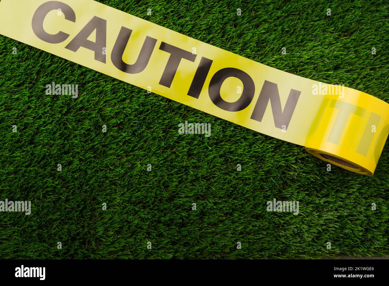 Close-up. Yellow plastic tape with the inscription CAUTION on a green ...