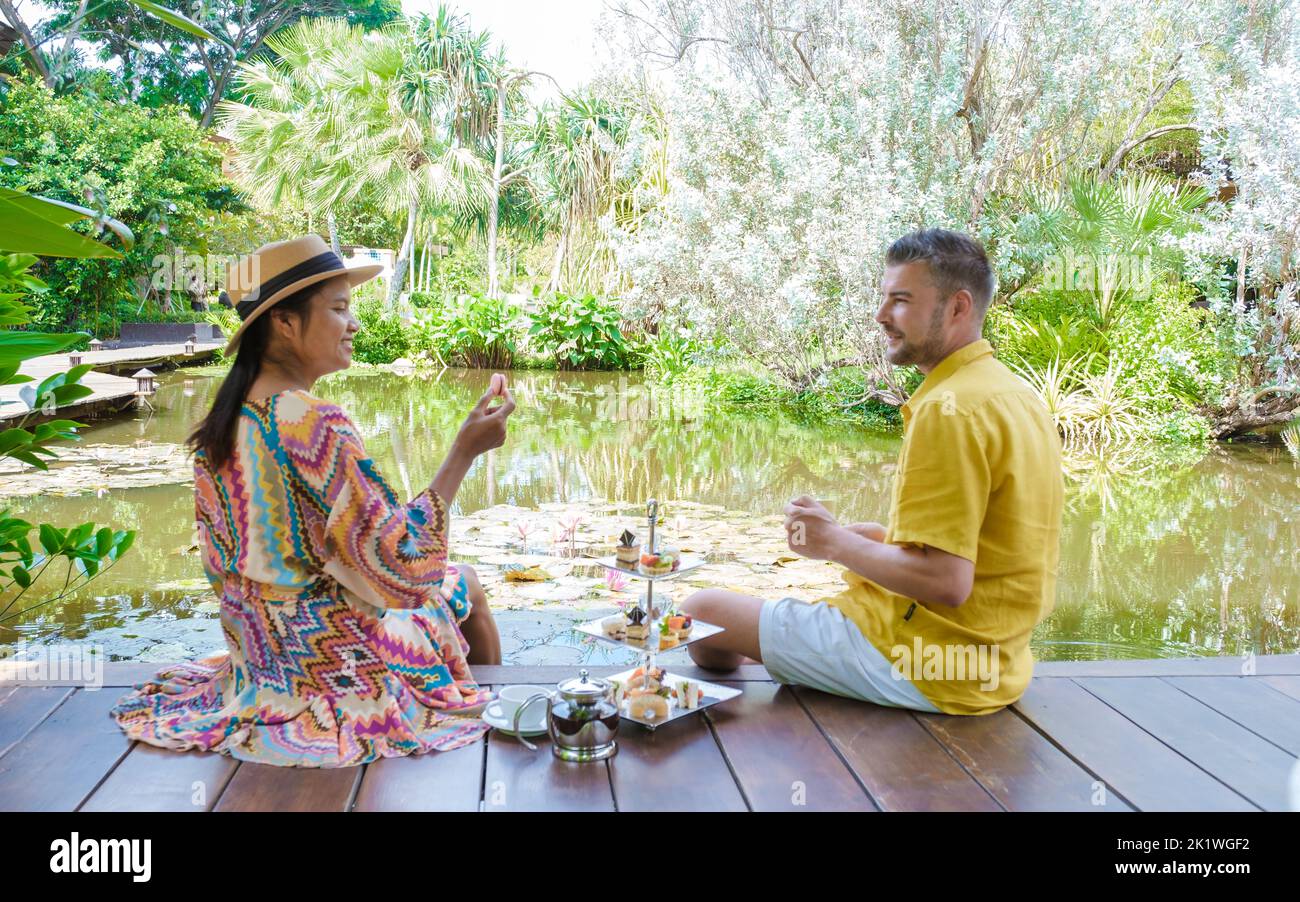 Afternoon tea at a water pond, high tea in a tropical garden in ...
