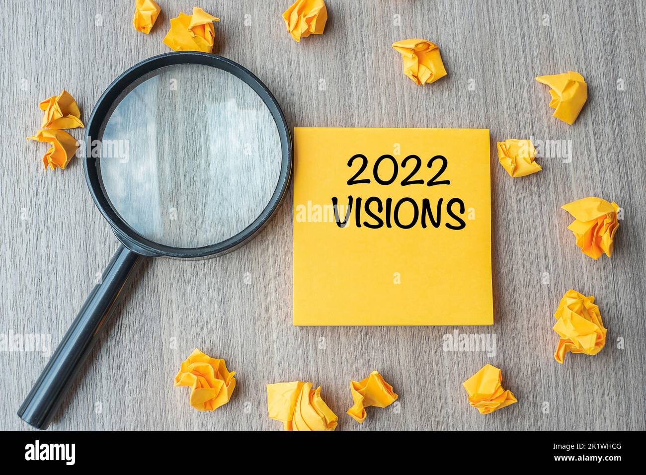 2022 VISIONS words on yellow note with crumbled paper and magnifying ...