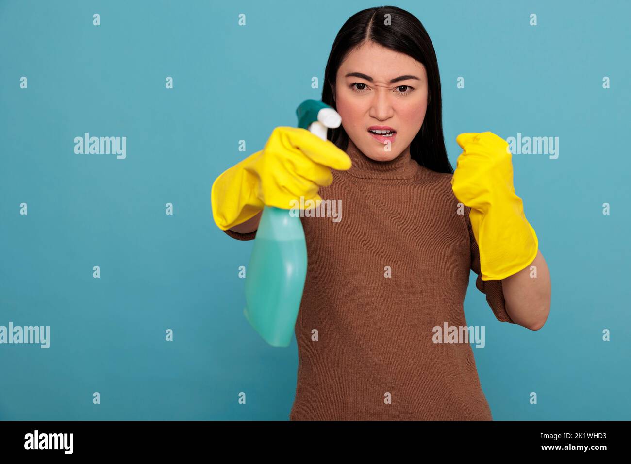 Angry frustrated asian young housewife in rubber gloves and detergent ...