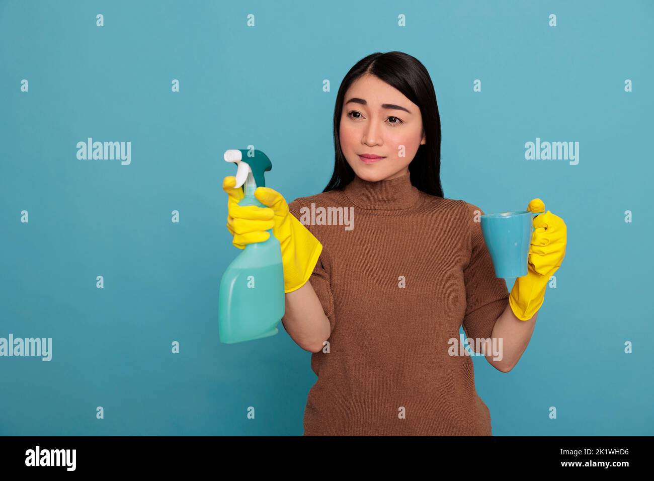 Sad depressed young housekeeper asian holding a spray and coffee cup ...