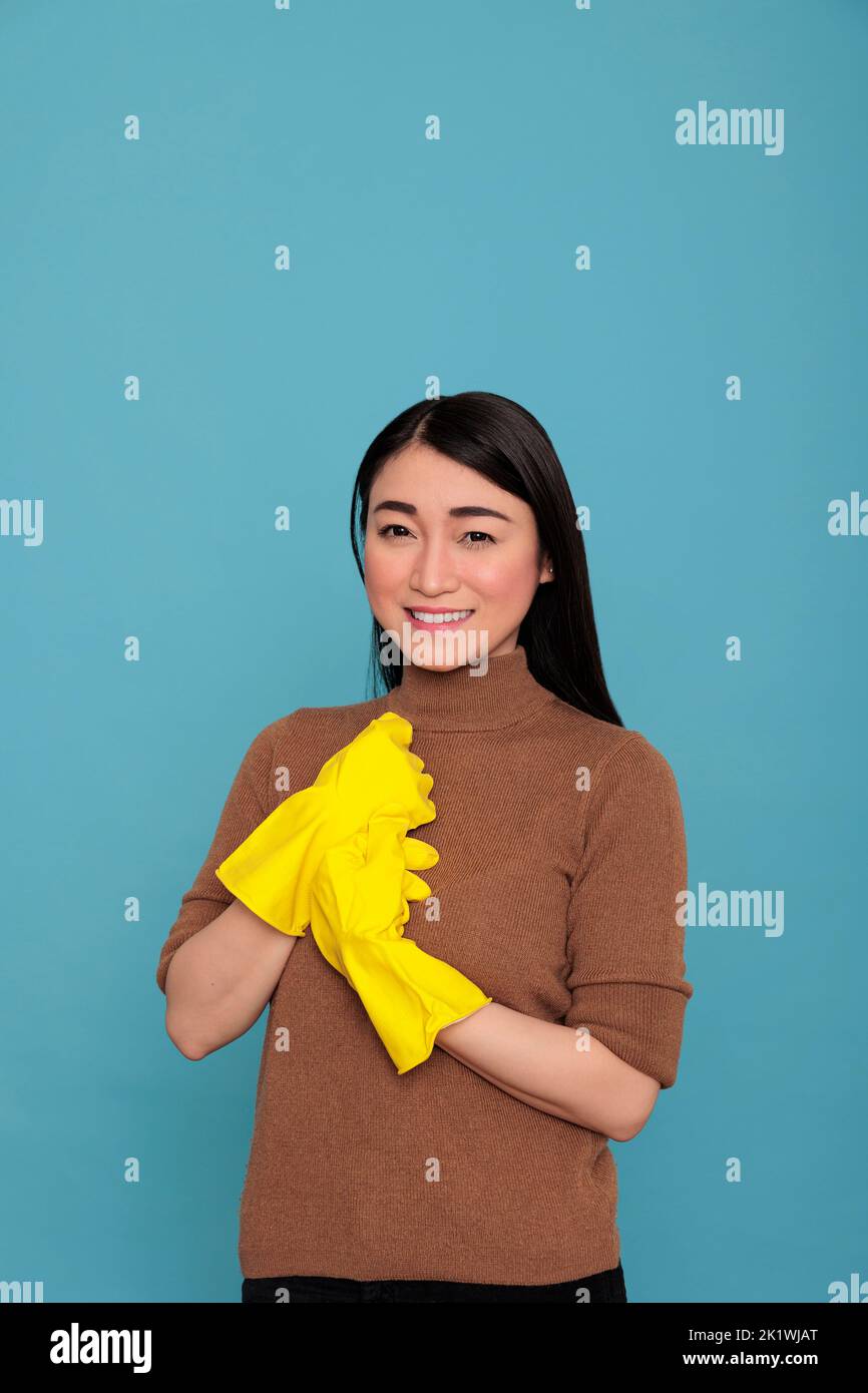 Mature smiling delighted asian housekeeper from housework holding hand ...