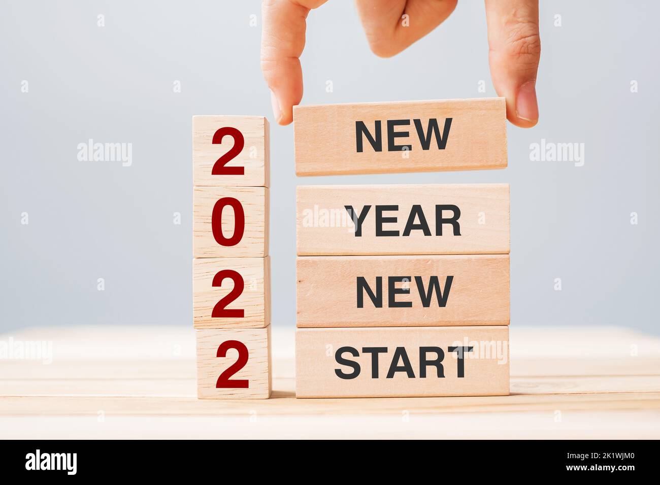 Businessman hand holding wooden block with text 2022 NEW YEAR NEW START ...