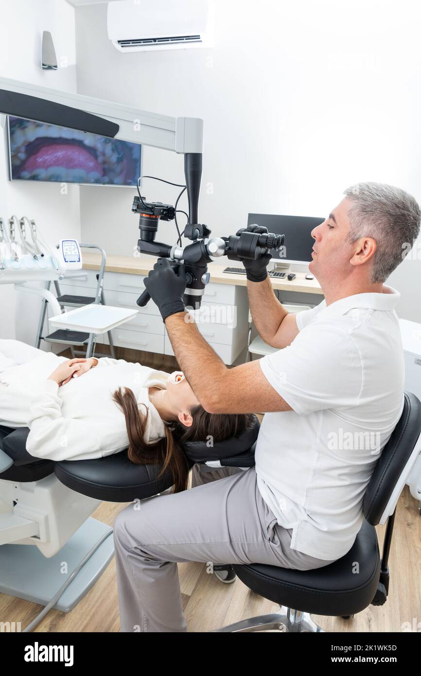 Dentist using dental microscope treating patient with braces in dental ...
