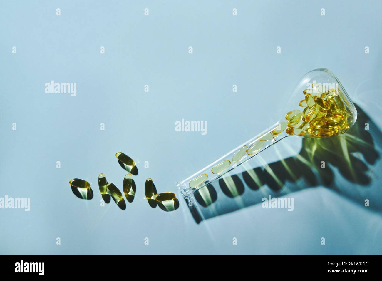 Capsules of omega-3 fatty acids on a blue background in a flask. The ...