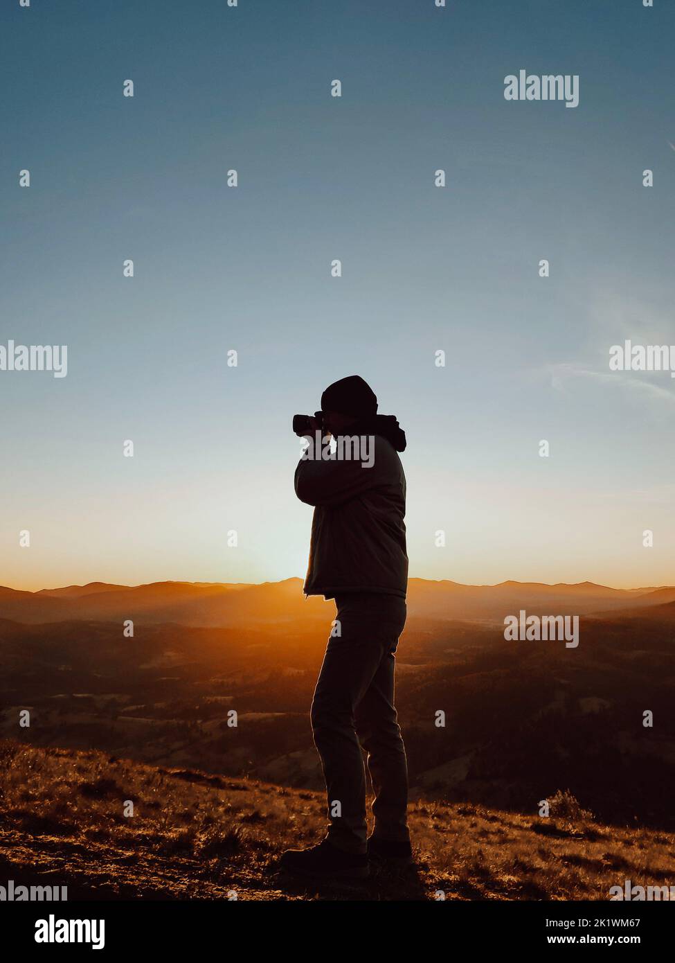 A man photographer taking pictures in front of autumn mountains ...