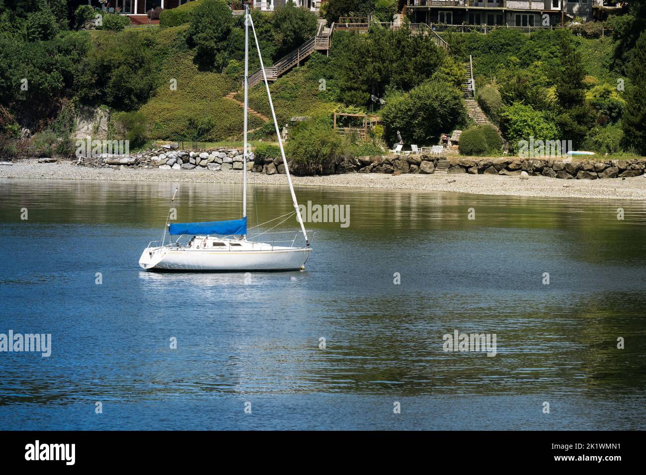 A small motor boat anchored in a cove of Bainbridge island with trees ...