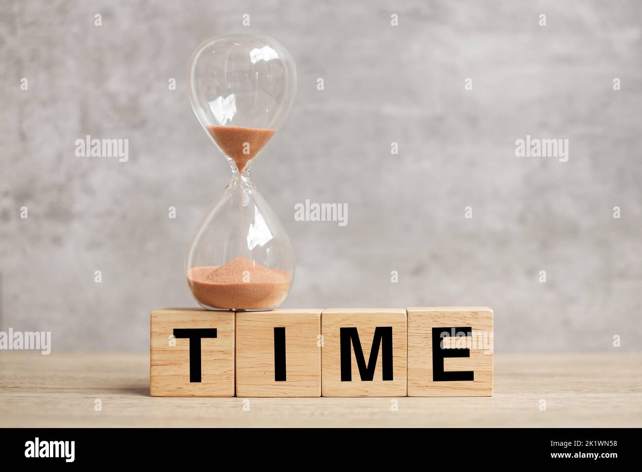 Hourglass with TIME block on table, Sand flowing through the bulb of ...