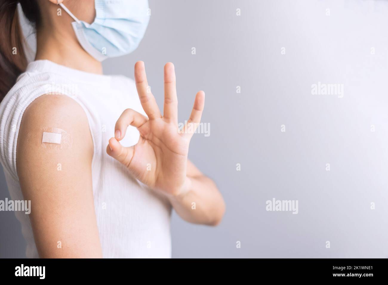 Happy Woman showing her arm with bandage and giving ok hand sign after ...