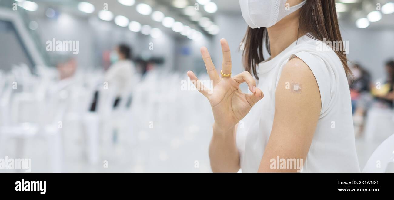 Happy woman showing her arm with bandage and giving ok hand sign after ...