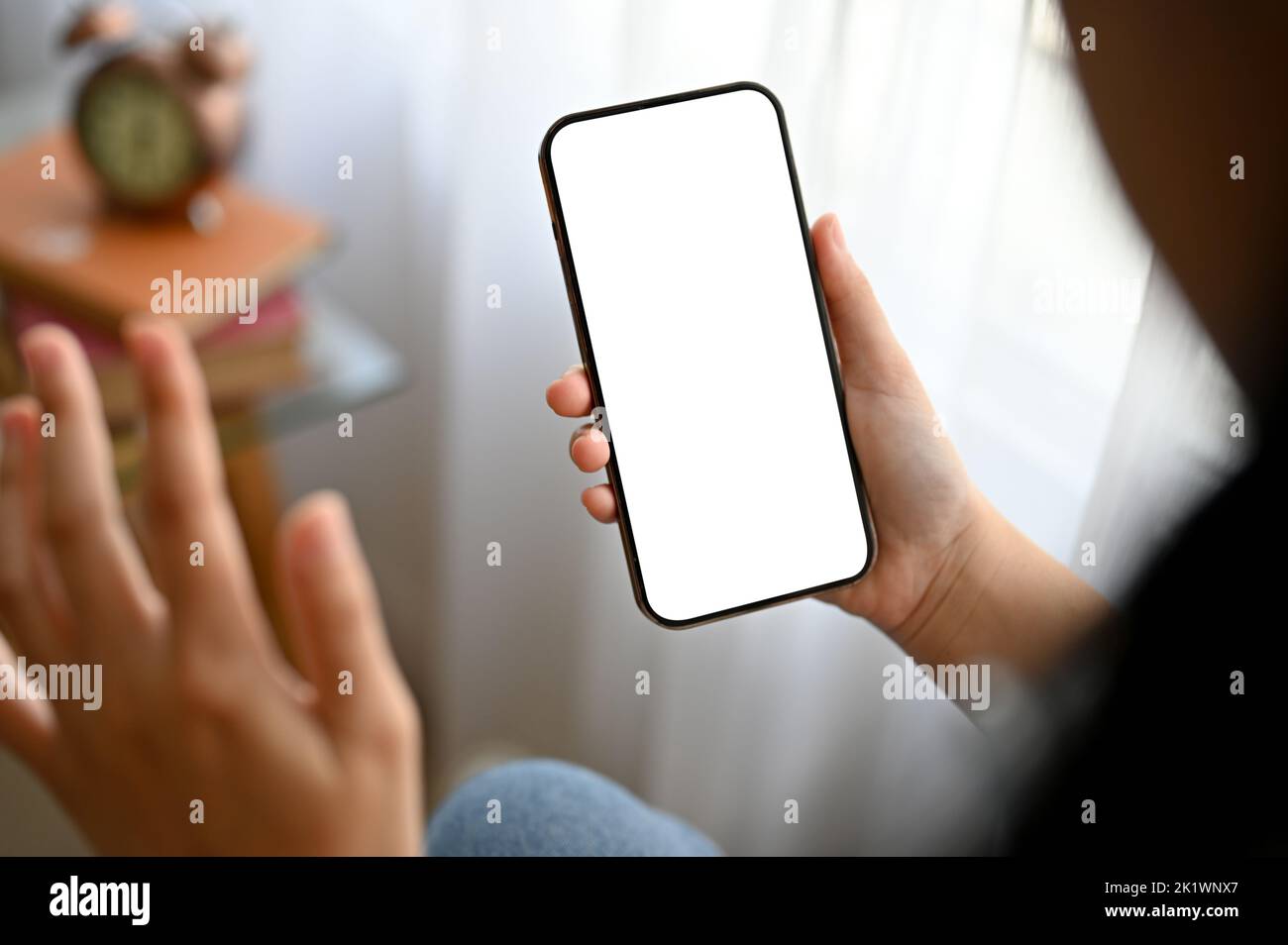 An Asian female holding a smartphone white screen mockup. A female ...