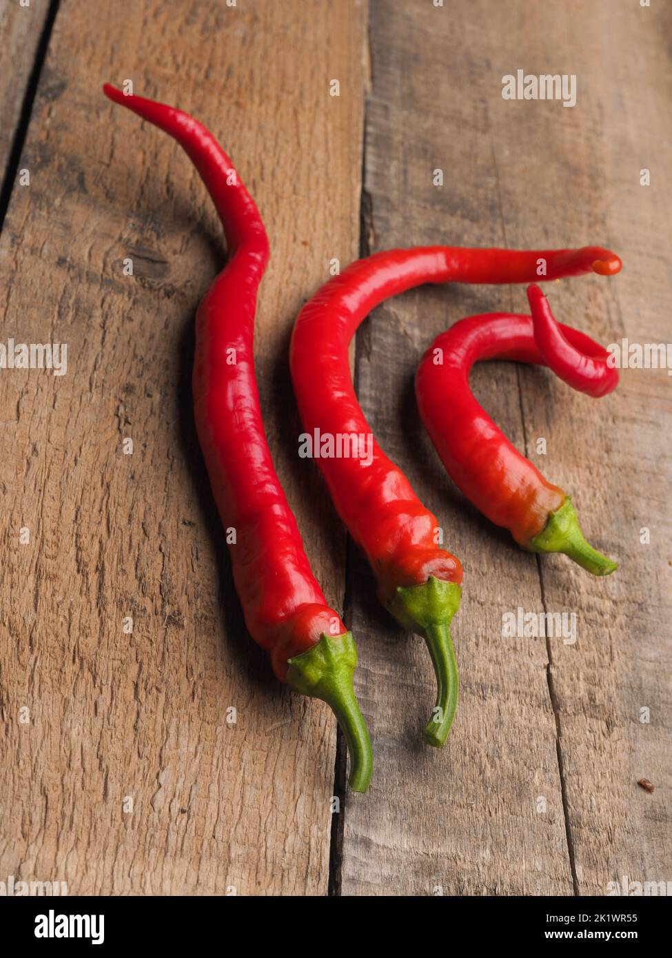 Three tasty organic chili peppers on a rustic wooden table, healthy ...