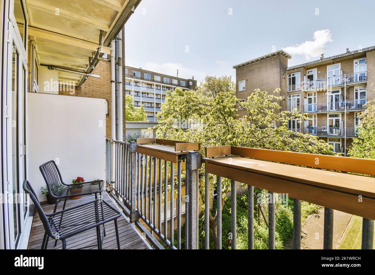 Narrow brick balcony with metal railings, wooden chair and door Stock ...