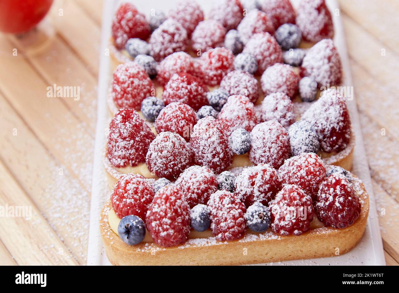 French blueberry and raspberry tartlets sprinkled with powder close up ...
