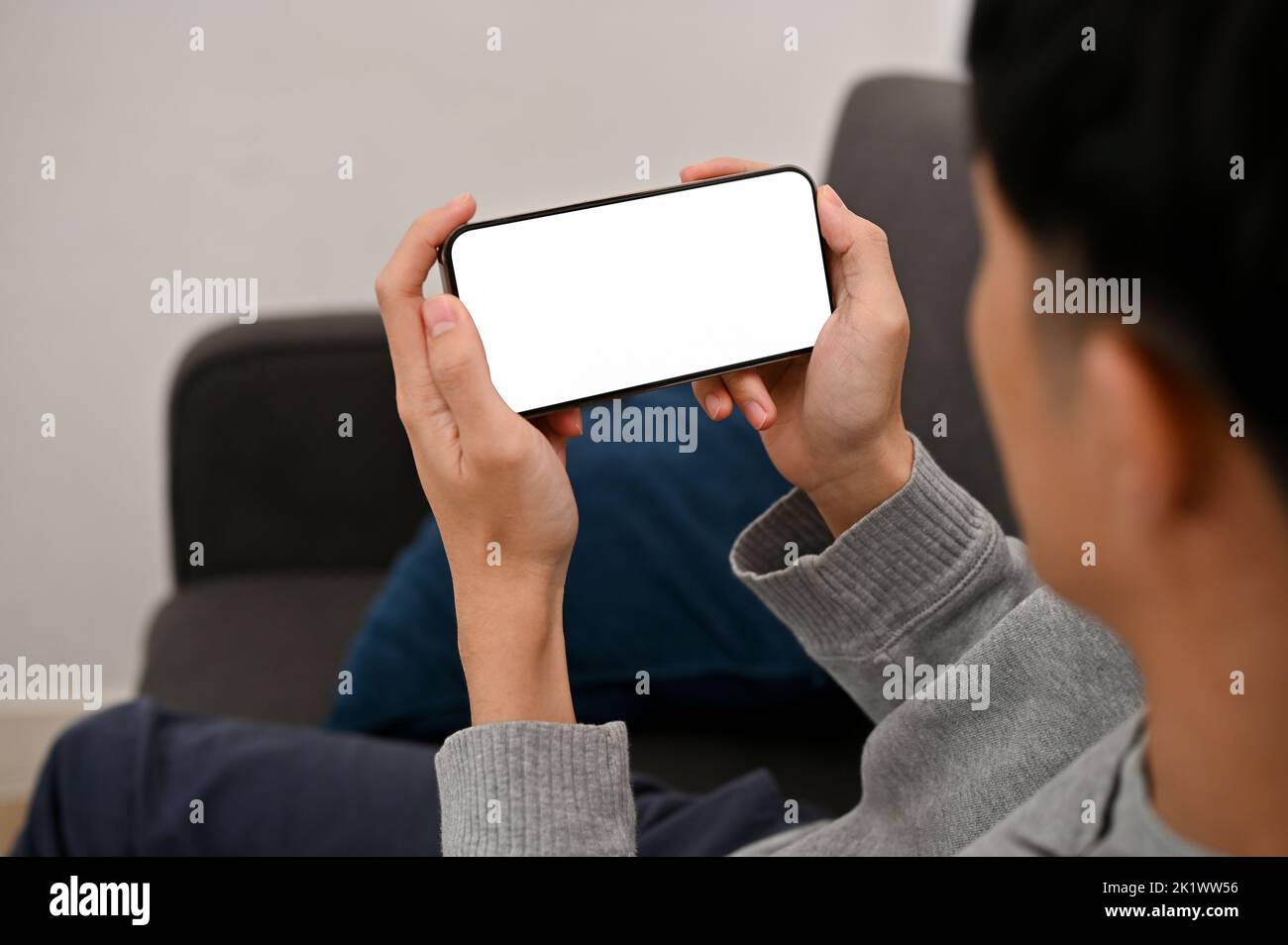 A young asian guy using his smartphone, watching video or playing ...