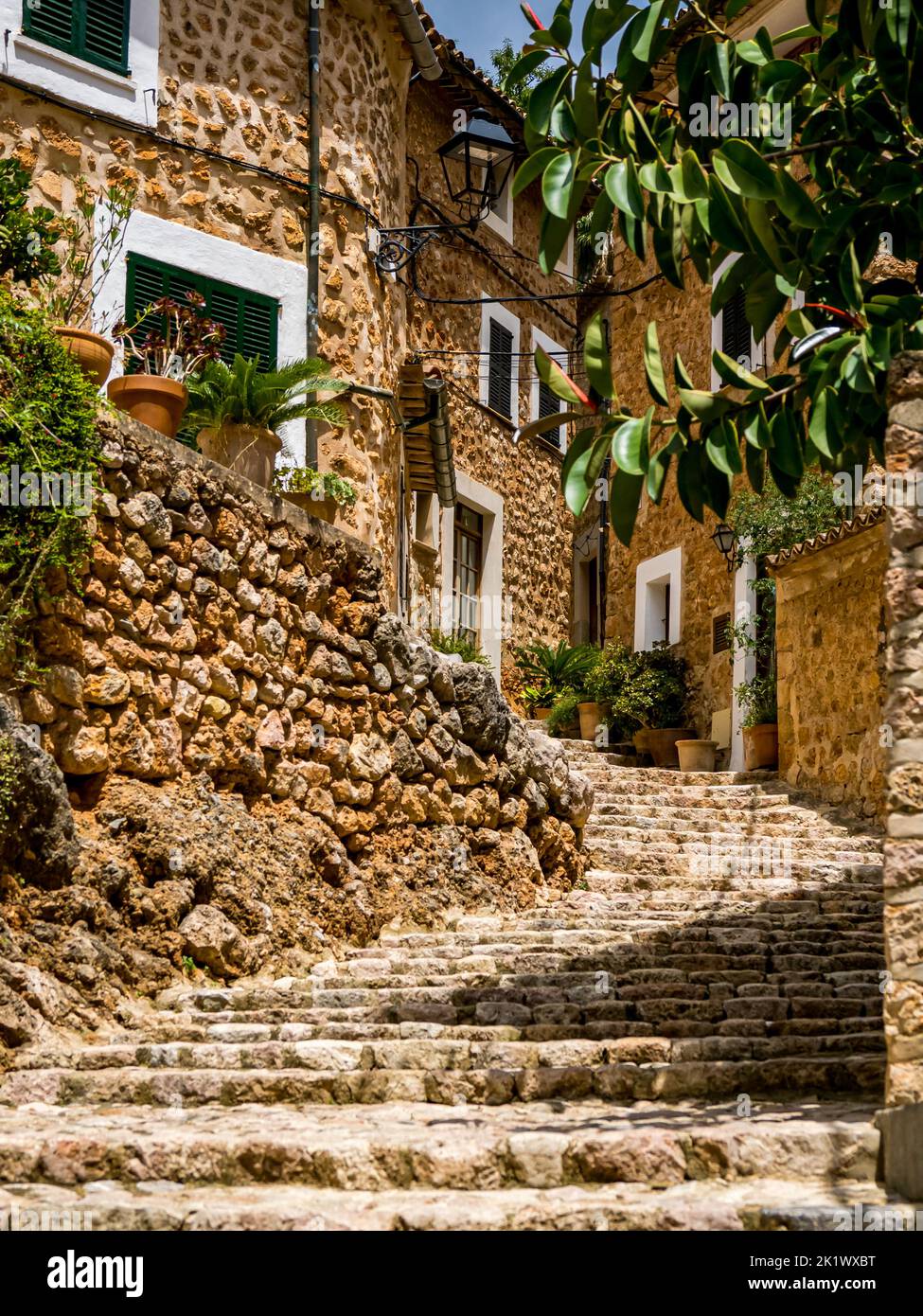 Narrow uphill alley named Carrer Església with curved cobbled steps in the idyllic mediterranean ...