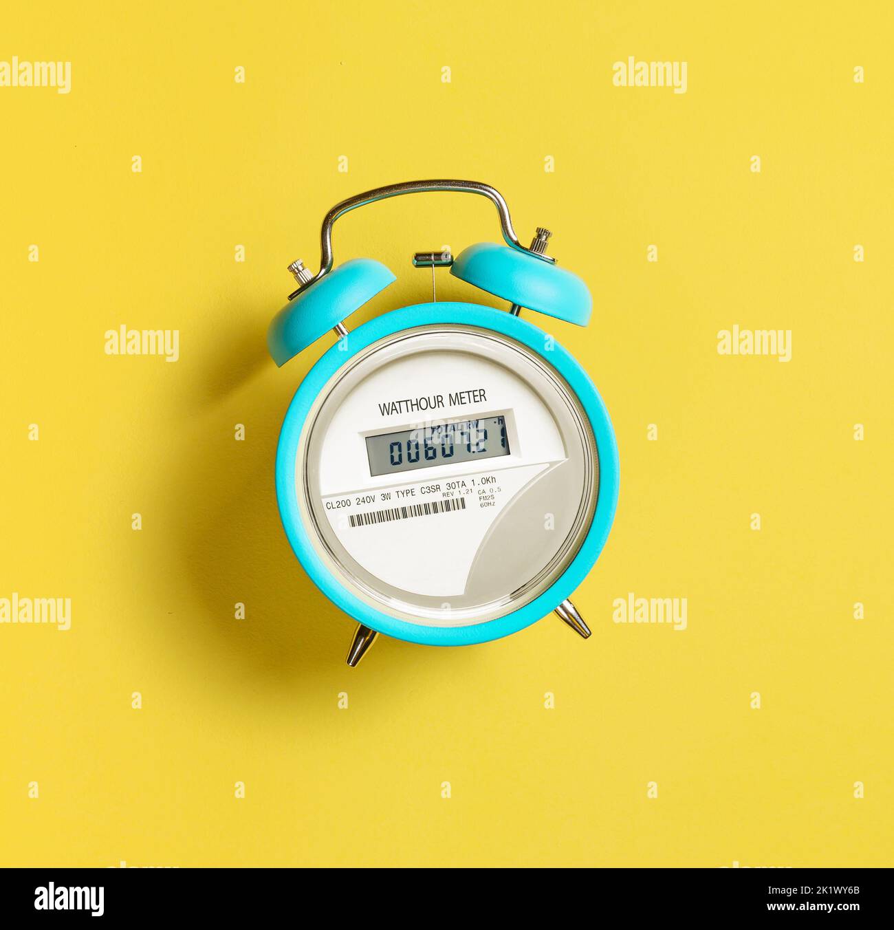 Electric meter with alarm clock on a yellow background Stock Photo - Alamy