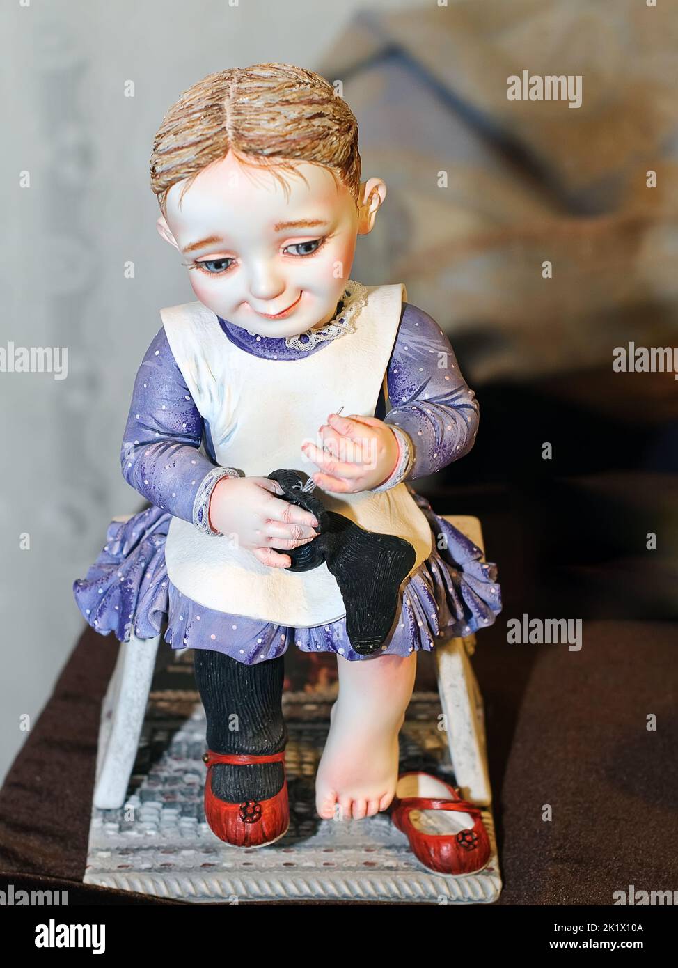 A collectible doll, a small girl mending up a black sock, is on display ...