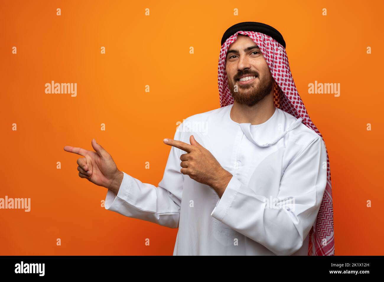 Young Arab man pointing hand to copy space on orange background Stock ...