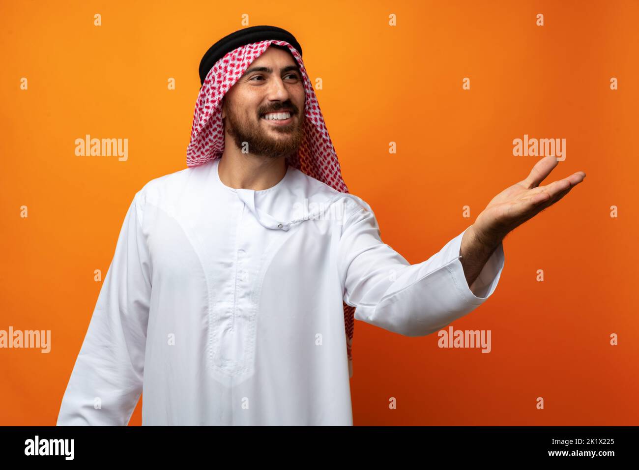 Young Arab man pointing hand to copy space on orange background Stock ...