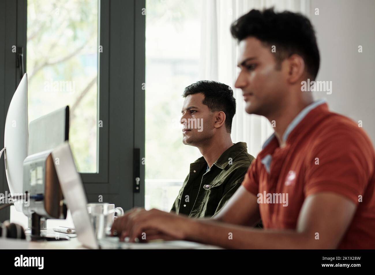 Concentrated software developers working on computers in modern office ...