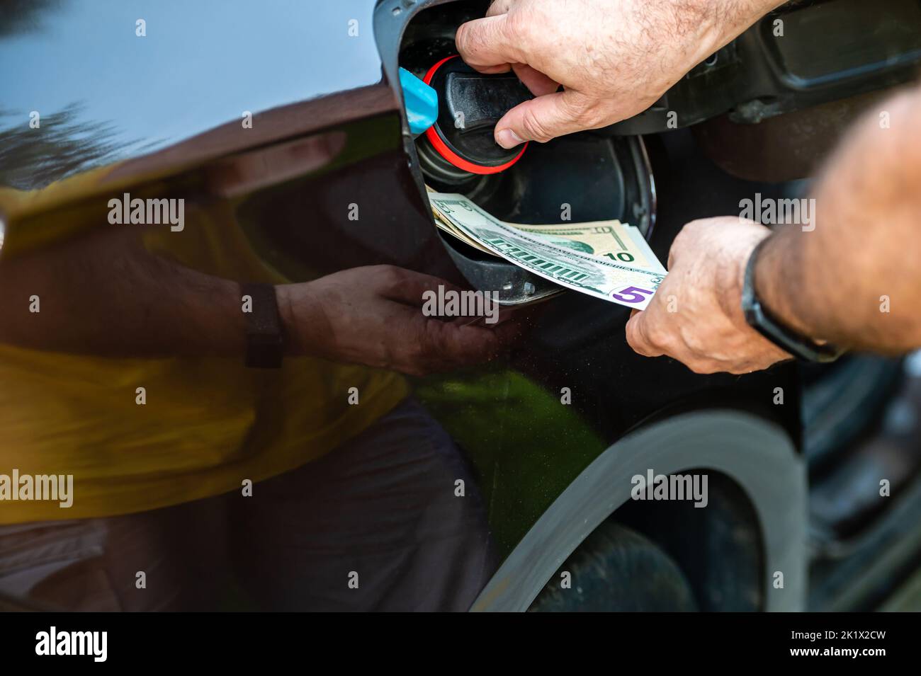 hand of man that puts money into the tank of car, close-up, concept of ...