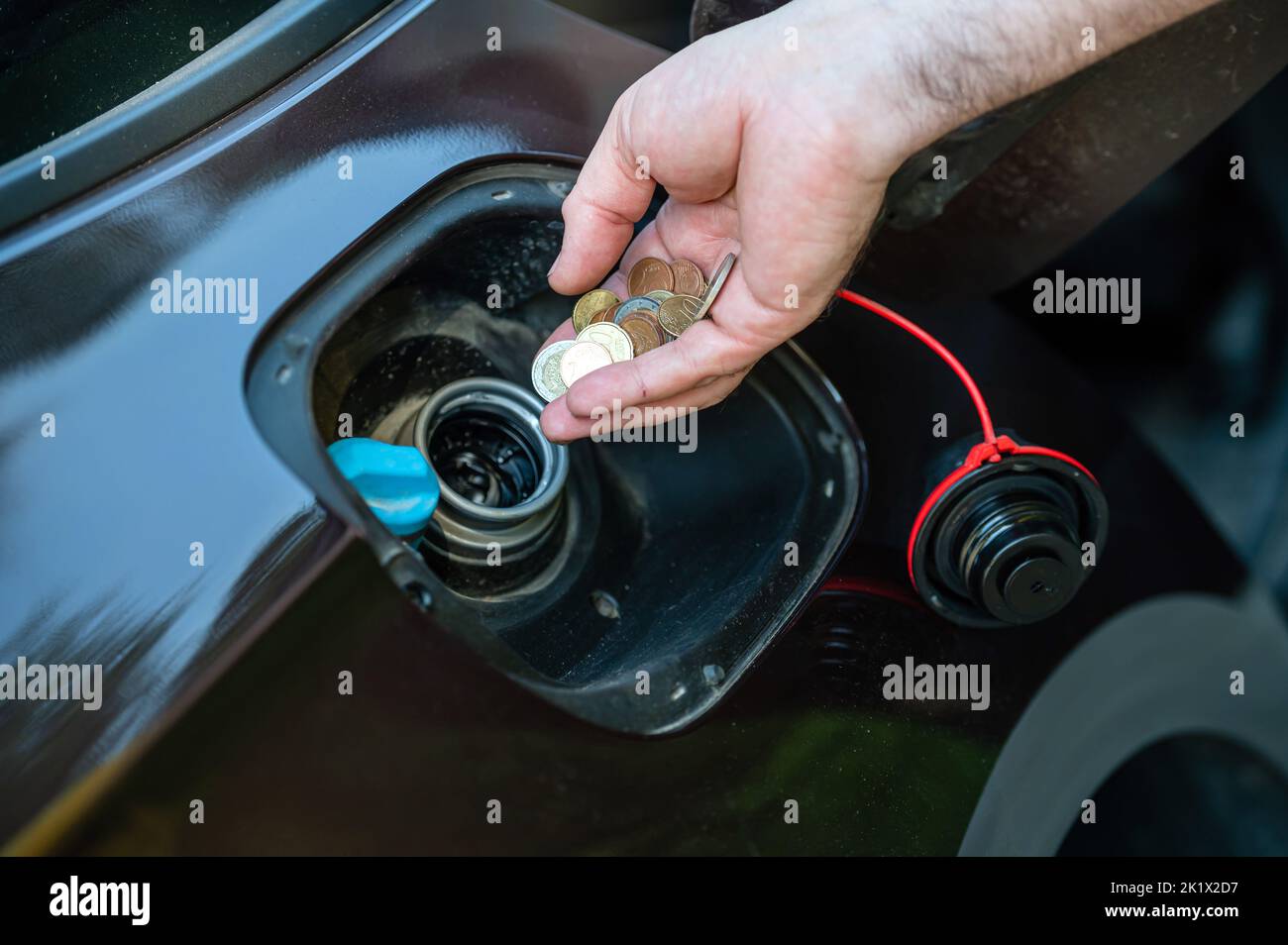 hand of man putting coins in car tank, close-up, expensive fuel concept ...