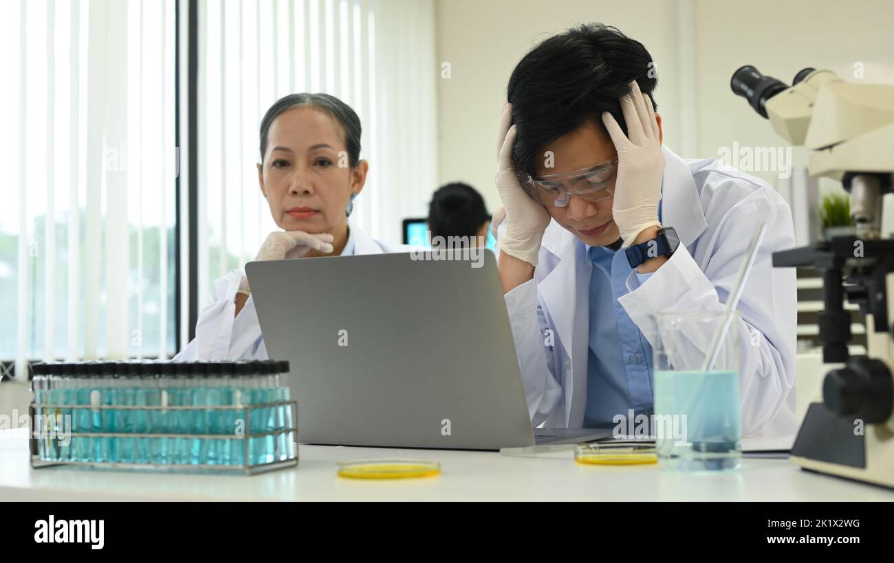 Professional scientists wearing white coats conducting experiment in ...