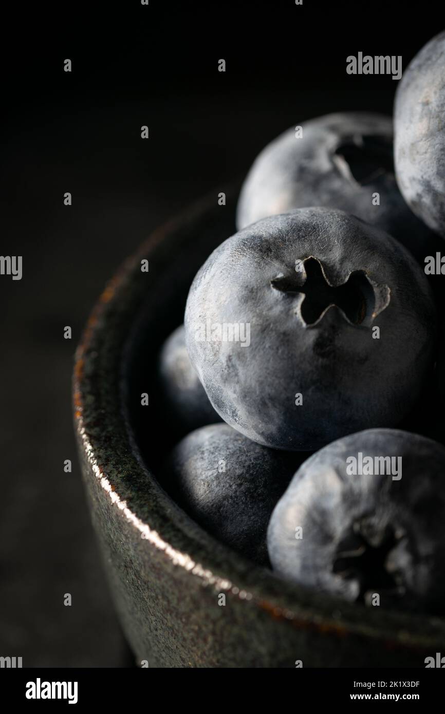 The vertical close-up view of a bowl of blueberries before the dark ...