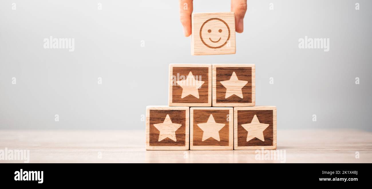 hand holding smile face over Star symbol blocks on table background ...