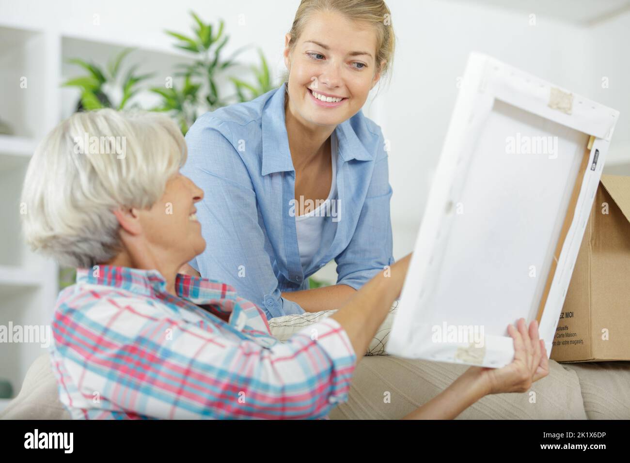 women looking at frame before hanging it Stock Photo - Alamy