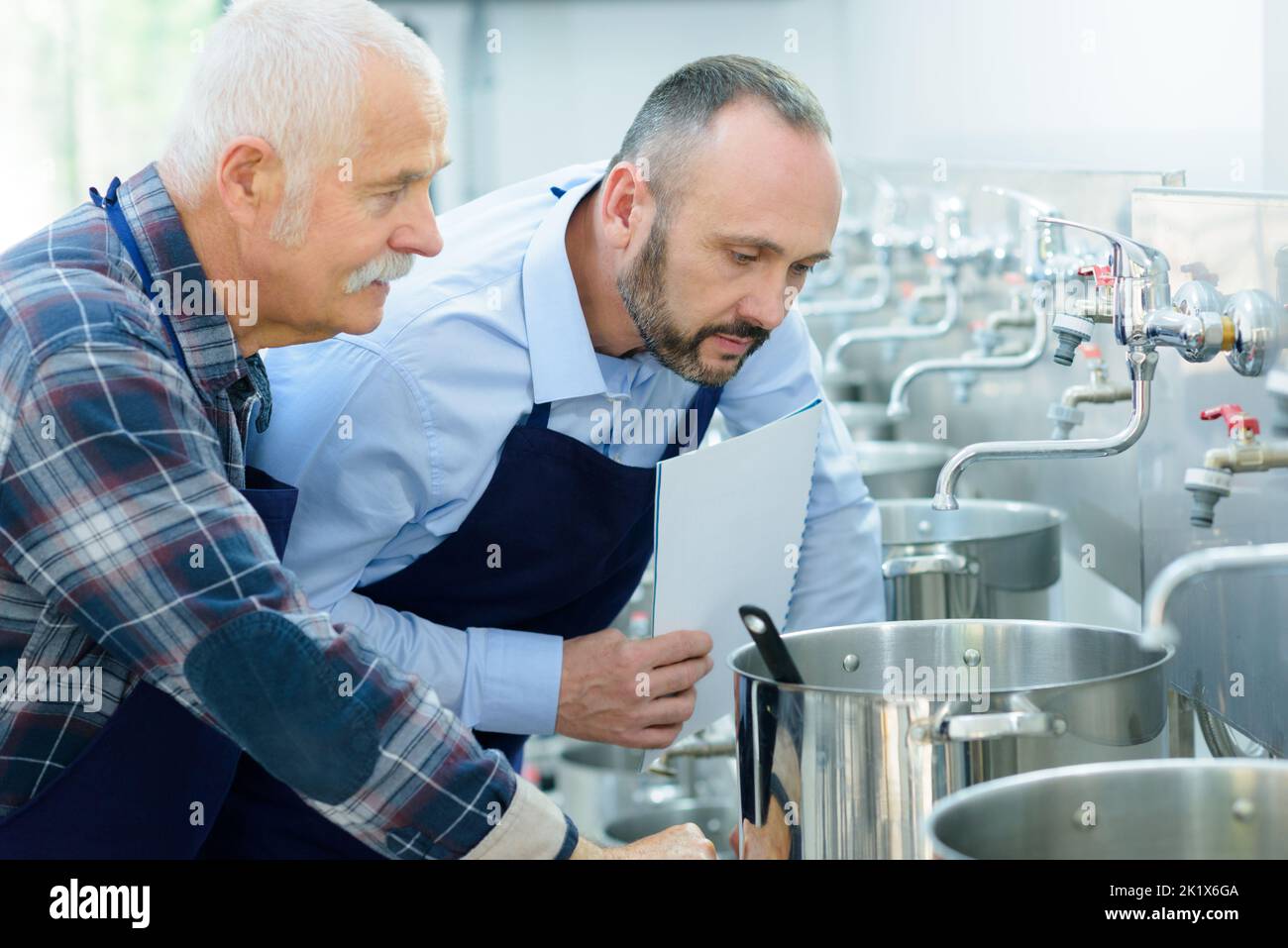 two male standing at factory in white overalls Stock Photo - Alamy