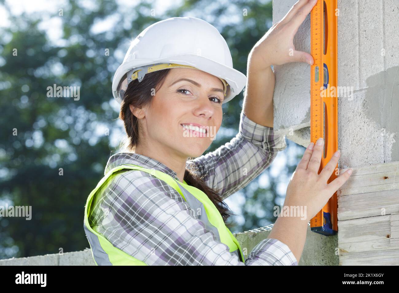 happy female constructor working with a level on a wall Stock Photo - Alamy