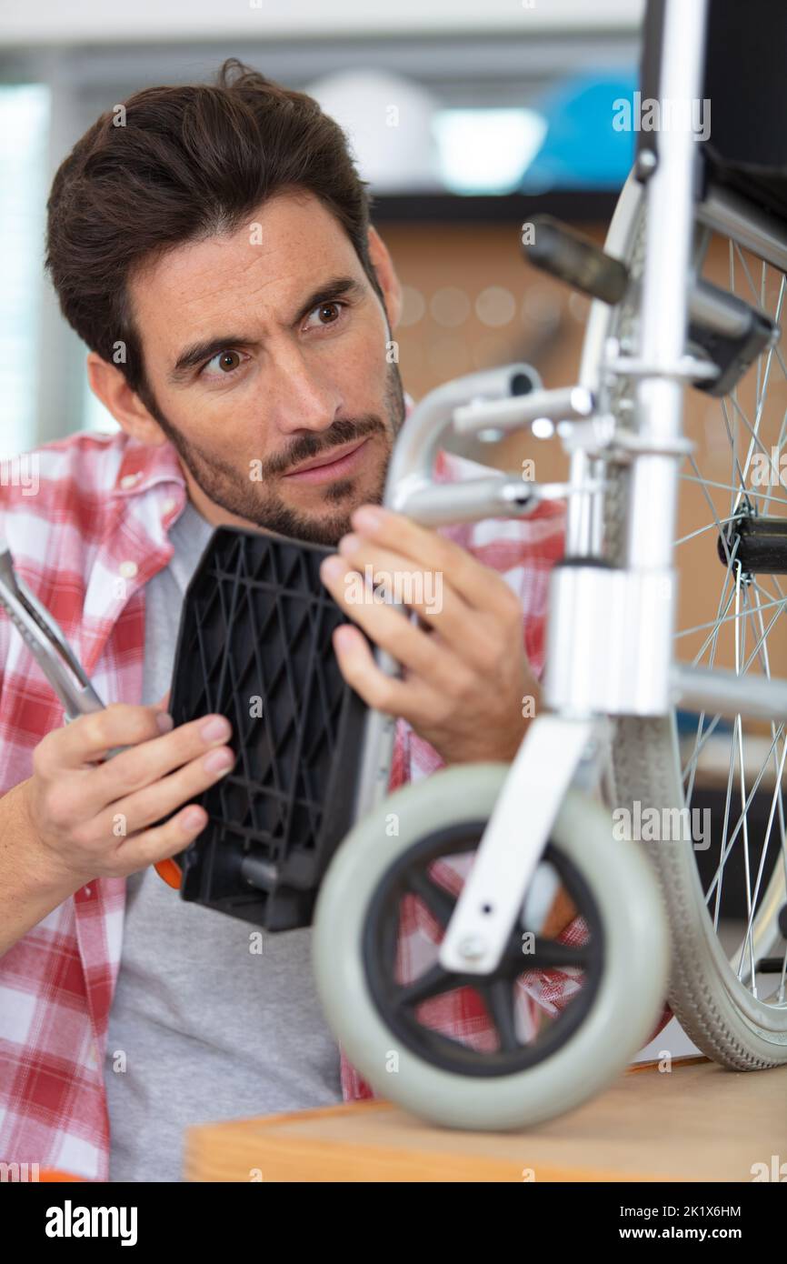 man is repairing a wheelchair in garage Stock Photo - Alamy