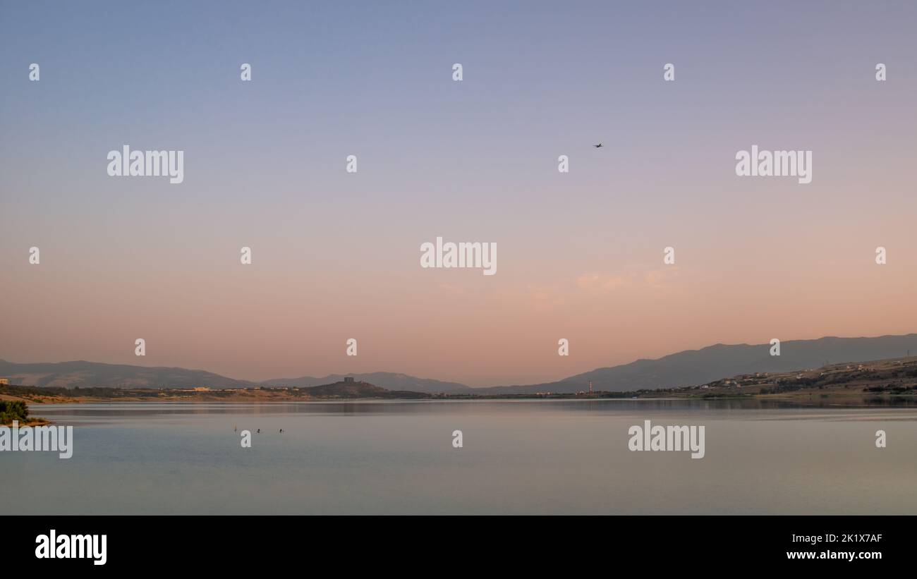 The view of waterside hills under the blue and purple shaded sunset sky ...