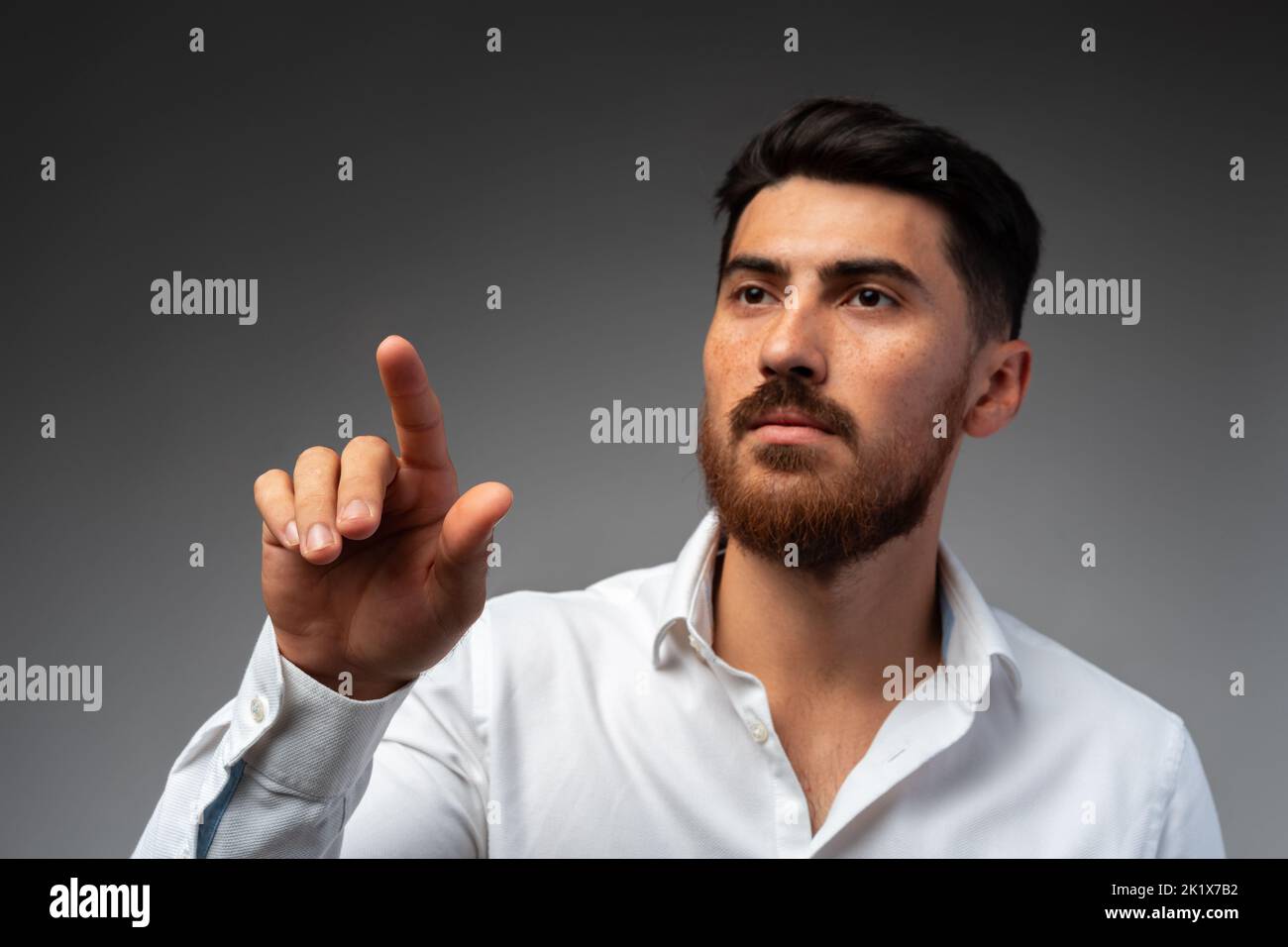 Young Arab businessman working with virtual screen over grey background ...