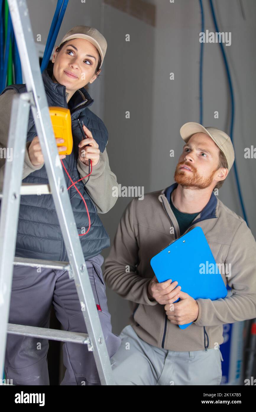 tradesman with female electrician on stepladder Stock Photo - Alamy