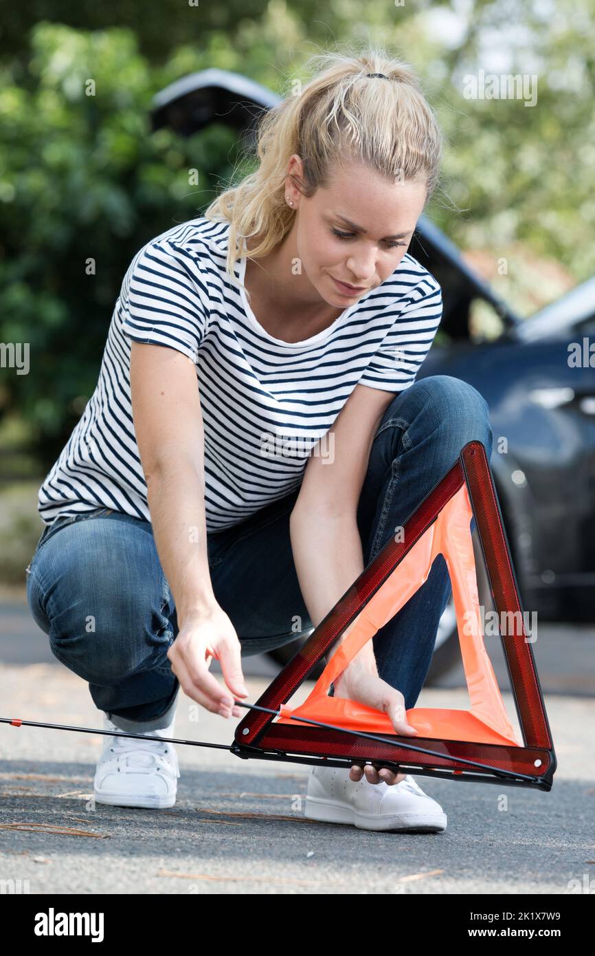 female motorist putting a safety triangle Stock Photo - Alamy